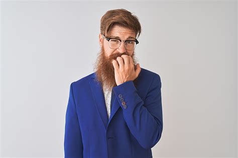 젊은 빨간 머리 아일랜드어 사업가 는 입물고 손톱에 손을 긴장 찾고 고립 된 흰색 배경 위에 양복과 안경을 착용 불안 문제 감정에 대한 스톡 사진 및 기타 이미지 Istock