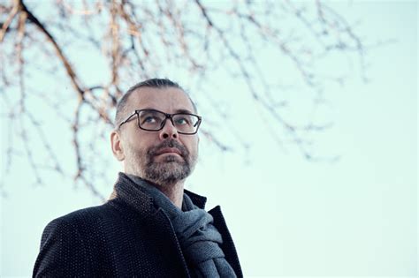 하늘을 배경으로 파란색 코트와 모직 스카프를 착용하고 안경을 쓴 자신감 넘치는 수염을 기른 중년 남성의 초상화 로우 앵글 뷰 40 49세에 대한 스톡 사진 및 기타 이미지