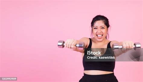운동 보디 빌딩 다이어트 건강 한 관리 개념 통통한 비만 플러스 크기의 미소 여자는 고립 된 분홍색 배경 위에 서있는 동안 체중 감량을위한 아령 운동을 들고 운동에 대한