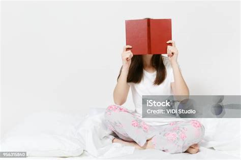 하얀 시트 베개 흰색 바탕에 담요와 침대에 앉아 젊은 행복 한 여자 룸에서 시간을 보내고 책을 읽고 책 뒤에 숨어에 여자를 아름다움 긴장 기분이 좋은 개념 텍스트에 대 한