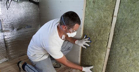 보호용 고글과 방독면을 착용한 작업자는 차가운 장벽을 위한 미래의 집 벽을 위해 나무 프레임에 암면 단열재를 단열합니다 편안하고 따뜻한 집 경제 건설 및 개조 개념