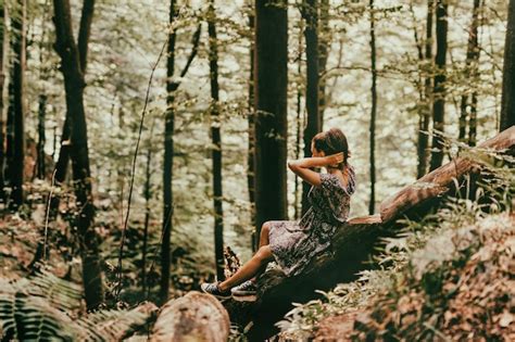 Premium Photo Side View Of Woman Sitting On Tree At Forest