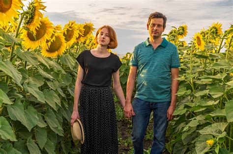 해질녘 에 해바라기 밭에서 걷는 사람들 아름다운 젊은 여자와 잘 생긴 성인 남자 시골 풍경에 대한 아버지와 딸 시골 주말 여행