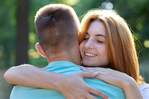 Beautiful Teenage Girl With Bright Red Hair Hugging Her Boyfriend