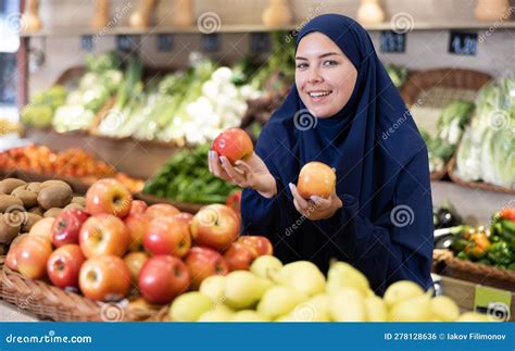 Delighted Young Muslim Woman Purchaser Choosing Apples In Grocery Store