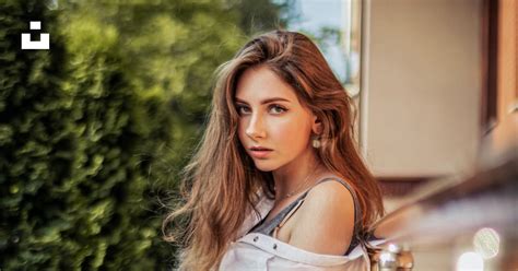 흰색 긴팔 셔츠와 회색 바지를 입은 여자가 낮에 녹색 식물 근처에 서 있다 사진 Unsplash의 무료 Россия 이미지