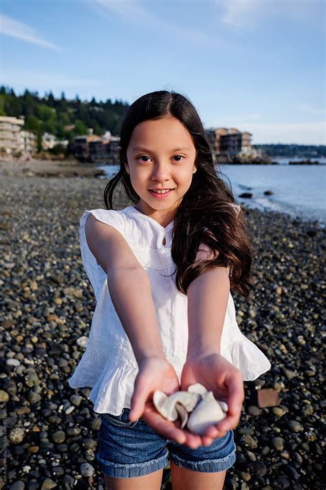 Mixed Race Girl Collecting Sea Shells On The Beach By Stocksy