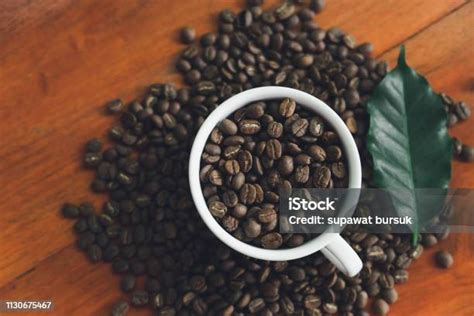 화이트 커피잔과 커피 콩 아름 답게 배열 나무 테이블에 Poured 커피 잎으로 장식 커피를 만들기 위한 원료의 혼합 0명에