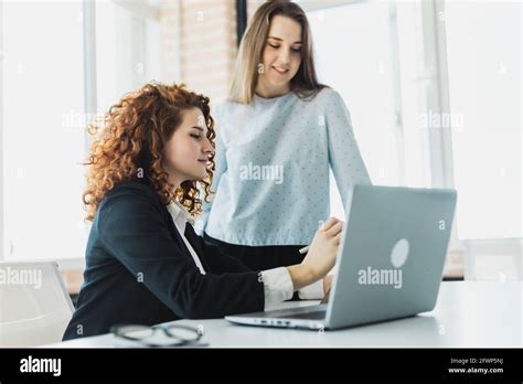 Two Beautiful Young Woman Talking And Discussing Working Moments With