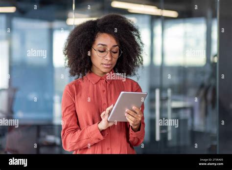 Serious Concentrated And Thinking Woman Using Tablet Computer Programmer Standing Near Window