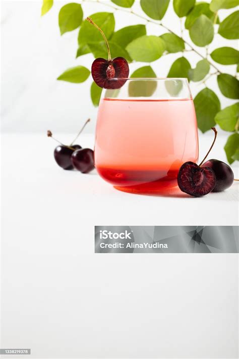 슬라이스 체리가 있는 미스트 글래스의 차가운 체리 레이어드 칵테일 부드러운 흰색 나무 테이블 대리석 벽 수직으로 햇빛에 녹색 신선한 잎 0명에 대한 스톡 사진 및 기타