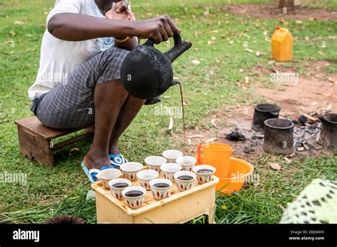Woman Pouring Traditionally Brewed Coffee Into Finjal Coffee Cup From A Jebena Coffee Pot