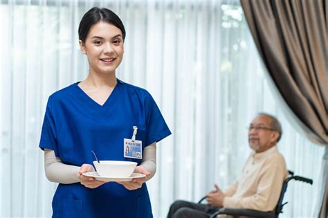 요양원에서 아시아 의 아름다운 여성 간호사의 초상화는 휠체어에 장애인 노인을 제공하기 위해 음식 그릇을 개최합니다 치료사 의사는 집에서 노인 환자를 돌봅니다 의료 방문 개념