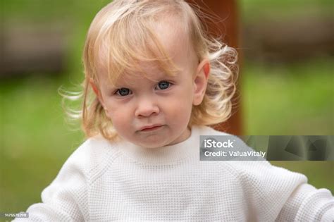 야외 놀이터에 앉아 카메라를 즐겁게 바라보는 행복한 아이 공원에서 미끄럼틀에 앉아 있는 귀여운 금발 아이 사랑스러운 미소를 짓는 백인 소년은 놀이터에서 놀이 시간을 보낸 후