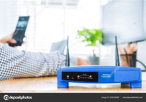 Closeup Of A Wireless Router And A Man Using Smartphone On Livin Stock Photo By Escapejaja