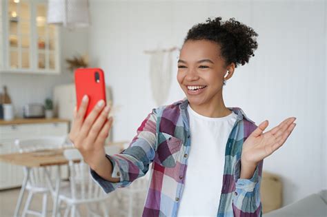 행복한 아프리카 계 미국인 소녀 블로거는 스마트 폰을 들고 화상 통화로 이야기하고 집에서 손을 흔들며 인사합니다 20 24세에 대한 스톡 사진 및 기타 이미지 Istock