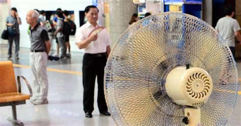 선풍기 앞에서 부채로 더위 식히고