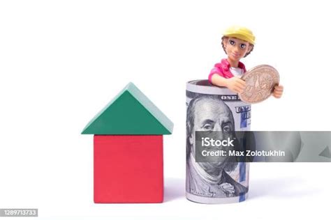 100 달러 지폐와 어린이 용 큐브로 만든 상징적 인 집에 1 미국 달러 동전을 가진 남자의 플라스틱 인형 0명에 대한 스톡