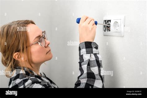 Woman With Screwdriver Repairing An Electrical Socket Woman Installing