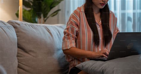 거실에서 노트북 키보드로 타이핑하는 젊은 여성의 손을 닫습니다 매력적인 아름다운 여성 직원 또는 학생은 어두운 밤에 집에서 일하고 공부하기 위해 컴퓨터를 사용하여 소파에