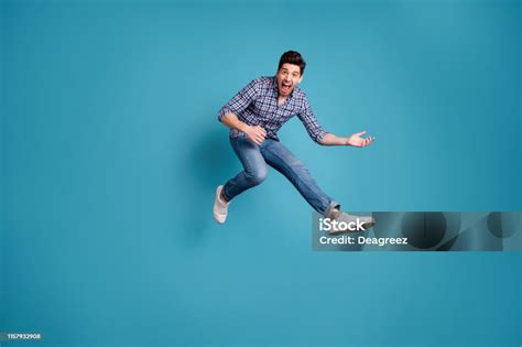 전체 길이 바디 사이즈 보기 사진 재미 매력적인 남자가 자유 시간 휴일 상상 록 스타 외침 손 꿈 꿈 장난 착용 현대 청바지 의상 운동화 고립 된 파란색 배경 점프에 대한