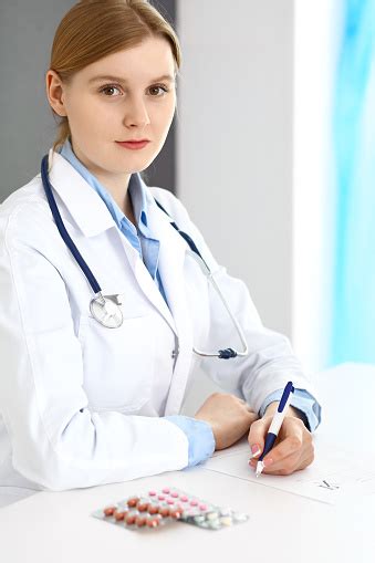 의사 여자 진료소 또는 병원에 창문 가까이 앉아있는 동안 처방전 또는 의료 기록 양식을 작성 의학 및 건강 관리 개념입니다 직장에서 의사 간호사에 대한 스톡 사진 및 기타