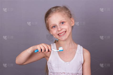 小女孩微笑着用牙膏和牙刷刷上了灰色