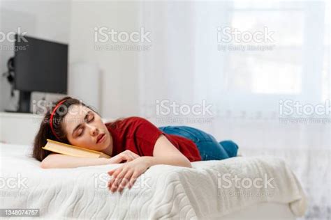 젊은 백인 여성이 침대에 누워 머리 아래 책을 들고 자고 있습니다 공간을 복사합니다 배경에 방의 흰색 인테리어 교육 및 교육의 개념 가정의 방에 대한 스톡 사진 및 기타