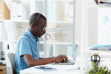 重度非洲穿戴耳机专心办公室膝上型计算机工作的便衣和零用笔记高清图片下载 正版图片504461189 摄图网