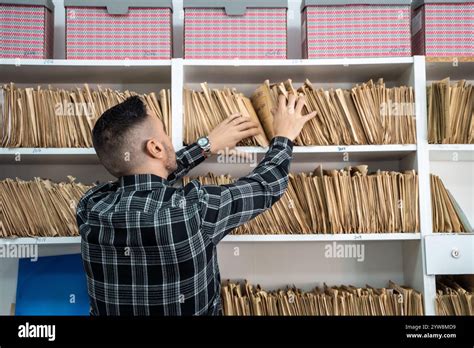 Office Worker Searching Files In Archive Room Filling Cabinet Checking Documents Organizing