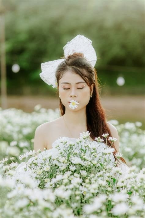 흰 꽃을 입에 물고 흰 드레스를 입은 여자 사진 Unsplash의 무료 이미지