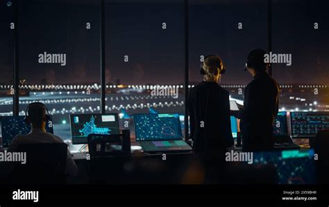 Female And Male Air Traffic Controllers With Headsets Talk In Airport
