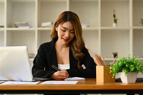 웃고 있는 사업가가 개인 일일 플래너에 메모를 쓰고 책상에 있는 노트북 앞에 앉아 있다 검사 보기에 대한 스톡 사진 및 기타 이미지 검사 보기 검색 경영자 Istock