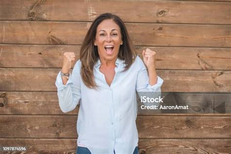 아름 다운 중 년 히스패닉 여자에서 자랑 비명과 축 하 하는 승리와 성공을 매우 흥분된 화창한 날에 나무 벽에 환호 하는 감정 응원함에 대한 스톡 사진 및 기타 이미지