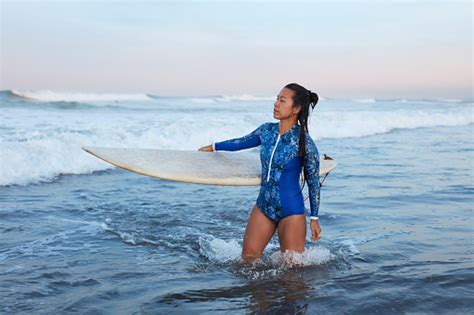 아름다운 서퍼 소녀 바다에 서 서핑 보드와 서핑 여자 갈색 머리 에 블루 잠수복 대기 파도 활동적인 라이프스타일을 위한 워터 스포츠 갈색 머리에 대한 스톡 사진 및 기타