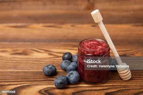 갈색 나무에 블루베리와 라즈베리를 곁들인 꿀 항아리 감기약 건강과 미용을위한 유용한 강화 잼 크림 꿀 채식주의 식단 유기농 제품