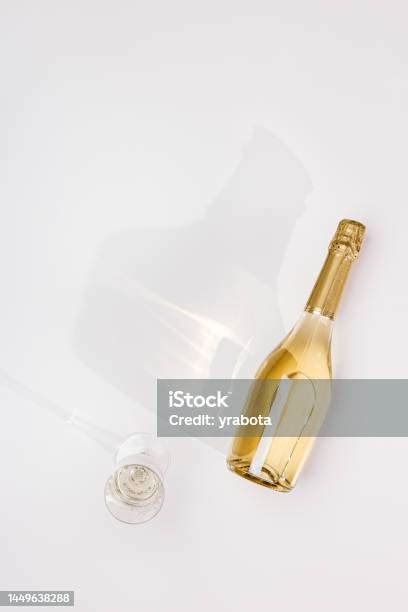 상위 뷰 화이트 스파클링 와인 병과 밝은 흰색 배경에 태양 그림자와 눈부심이 있는 유리 와인 평평한 황금 샴페인 병 축제 여름