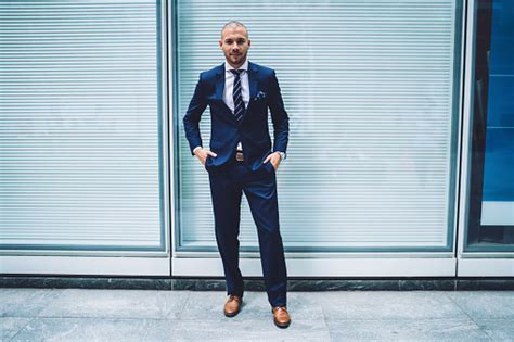 복사 공간 영역과 벽에 거리에 서 비싼 정장에 성공적인 젊은 남자 자랑 Ceo의 전체 길이 초상화 주머니에 손을 잡고 카메라를