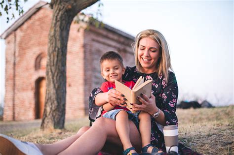 봄 정원에서 야외 아들에 대 한 책을 읽고 어머니 가족 피크닉에 함께 시간을 보내고입니다 여름 방학에 아이 들을 교육 하는 부모 2명에 대한 스톡 사진 및 기타 이미지