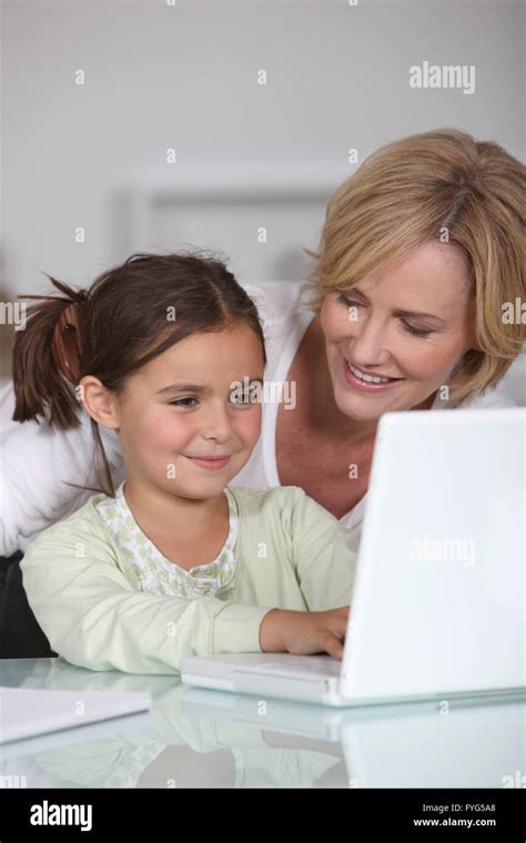 Mother And Young Daughter Using A White Laptop Computer Together Stock