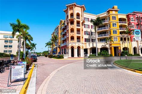 레스토랑과 푸른 하늘이 여러 가지 색이 있는 활기찬 색상의 커뮤니티 쇼핑 센터에 야자수가 있는 베이프론트 아파트 건물 나폴리 Collier County에 대한 스톡 사진