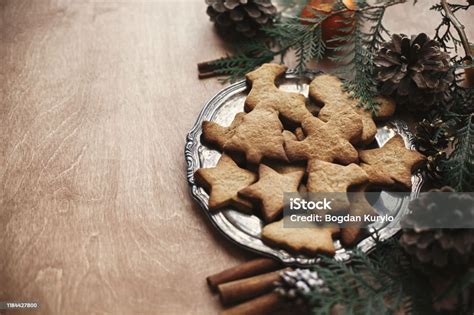빈티지 접시와 아니스 생강 계피 소나무 콘과 텍스트 공간이있는 소박한 테이블에 삼나무 가지에 크리스마스 진저 브레드 쿠키 전통적인 진저 브레드 쿠키 굽기 0명에 대한 스톡