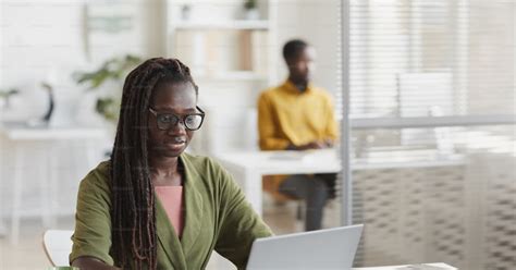 현대 아프리카계 미국인 여성의 초상화는 하얀 사무실 내부의 책상에서 일하는 동안 노트북을 사용하며 공간을 복사한다 사진 Unsplash의 책상 이미지