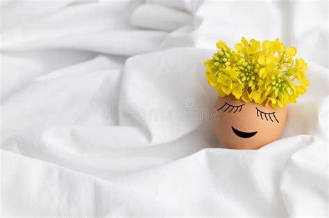 Easter Egg With Cute Face And Wreath Of Yellow Flowers On White Fabric