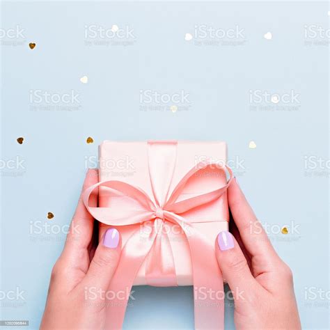 하트 모양 색종이 카피 스페이스와 파스텔 블루 배경에 분홍색 색상의 선물 상자를 들고 여자 손 트렌디 한 색상의 발렌타인 데이 인사말 카드 해피 발렌타인 데이 배경 개념에