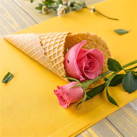 a delicate rose bud placed in a waffle cone resting on a bright yellow