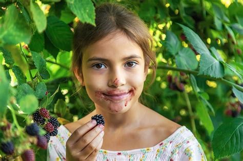 Premium Photo Portrait Of Smiling Girl Eating Black Raspberry