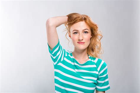 회색 배경에 스튜디오에 블루 스트립 여름 드레스에 붉은 곱슬 머리를 가진 젊은 아름 다운 여자의 클로 우즈 업 초상화 여름 휴가 관광 및 여름 옷의 테마 곱슬 머리에 대한