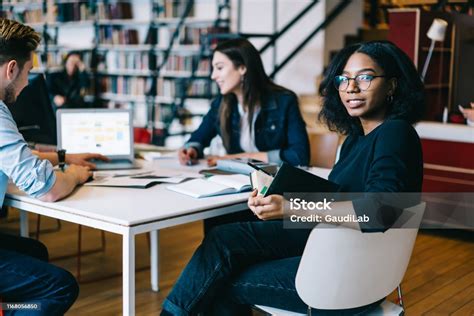 대학 도서관에서 학생들의 그룹과 워크샵을 갖는 전문 아프리카 계 미국인 여성 교사의 초상화 심각한 어두운 피부 여자 학습 및 친구들과 함께 프로젝트 팀 워크를 계획 계획에