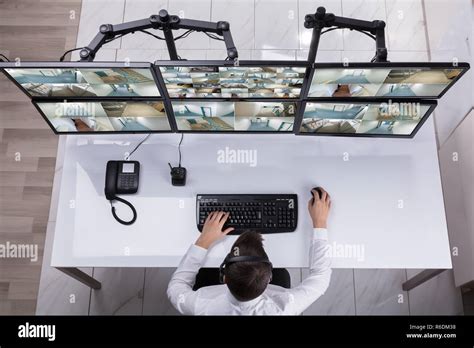 Security Guard Monitoring Multiple Camera Footage On Computer Stock